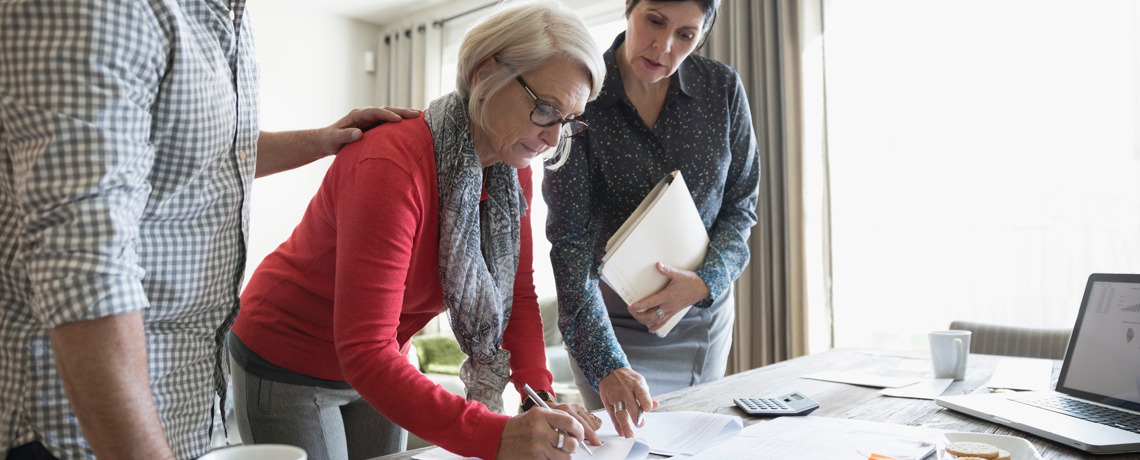 Retirement aged Caucasian couple with female signing paperwork while ...